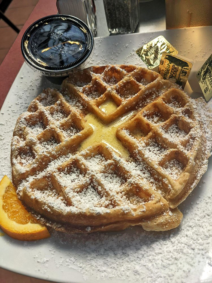 A Belgian waffle dusted with powdered sugar snow, waiting to be drowned in syrup like a delicious winter wonderland.