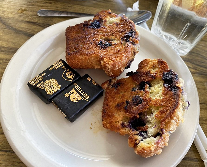 Blueberry muffins with the perfect crust-to-crumb ratio, served with butter packets that won't be returning to the kitchen unused.
