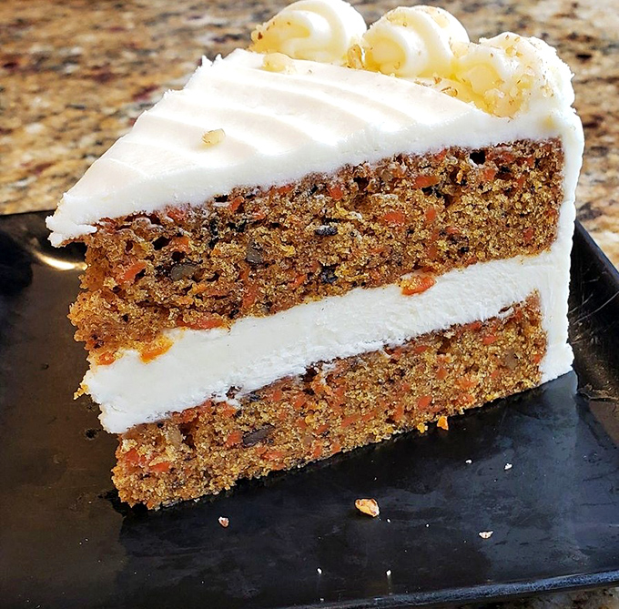 Carrot cake that makes you question why anyone bothers with birthday cake. That cream cheese frosting layer is thicker than most novels.