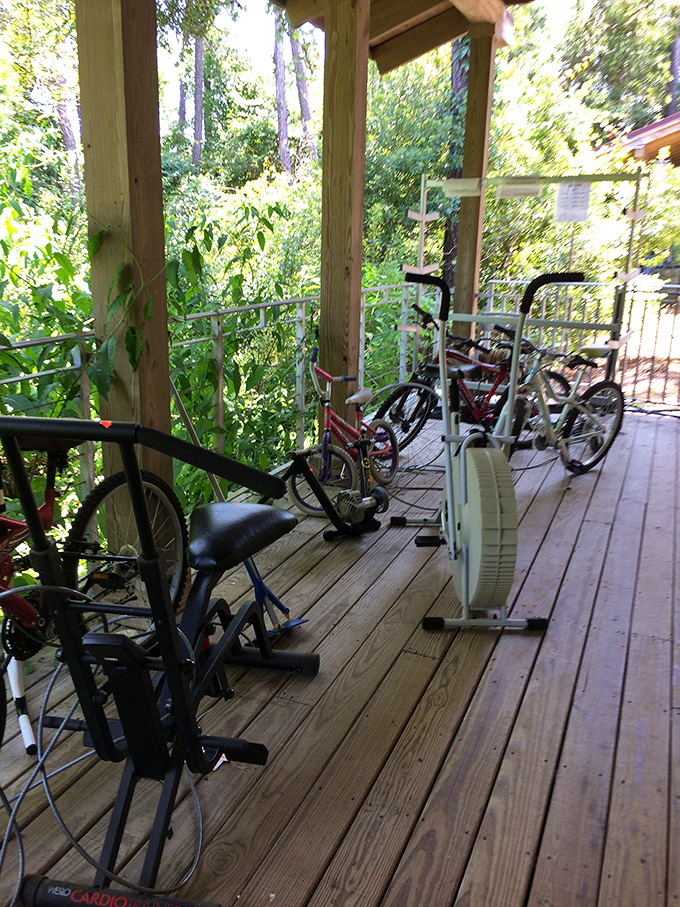 Exercise equipment and bicycles taking a breather on the porch. These wheels and pedals are just waiting for their next journey. 