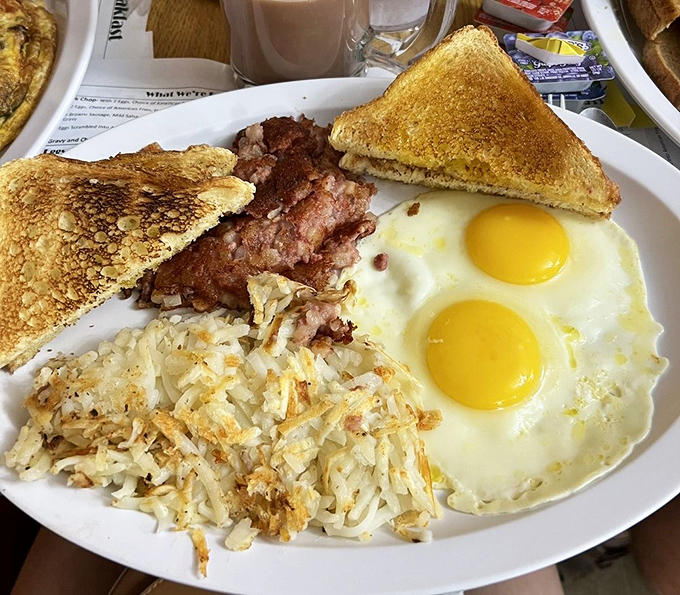 The breakfast trinity: perfectly sunny eggs, crispy hash browns, and toast waiting to soak up every last bit of yolk. Simple pleasures executed with expert precision.