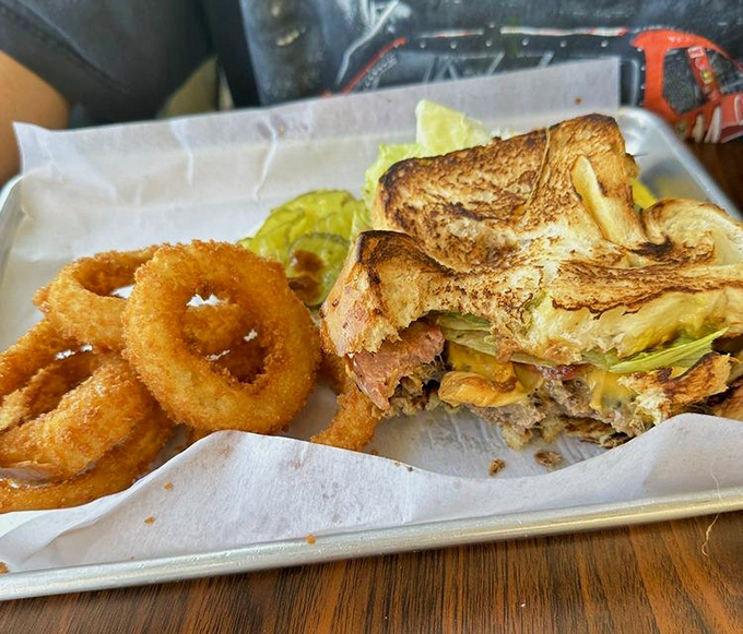 The sandwich that requires both hands and a strategy. Crispy onion rings standing guard like delicious sentries.