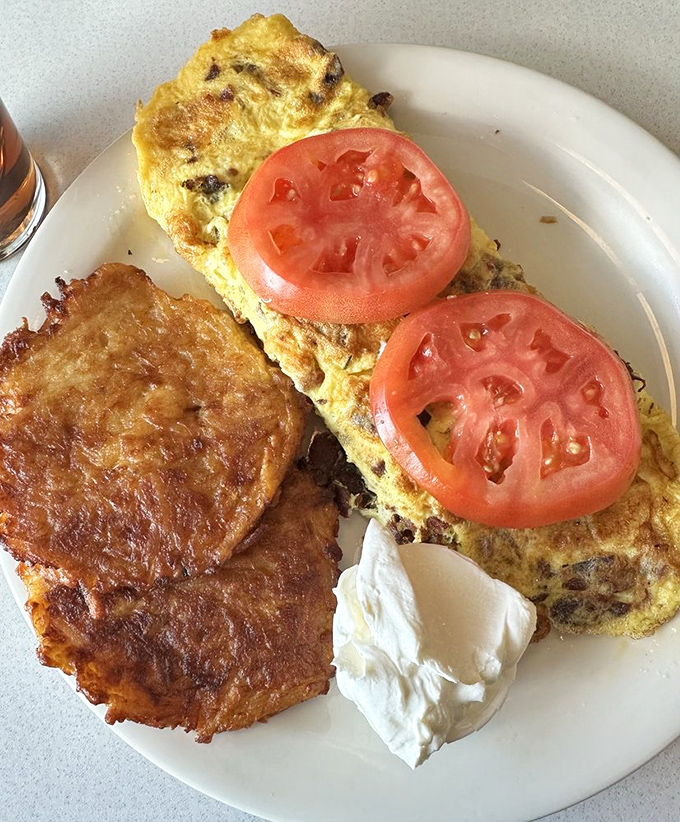An omelet that's seen things, flanked by perfectly crisped potato pancakes and a dollop of sour cream. Breakfast of champions.