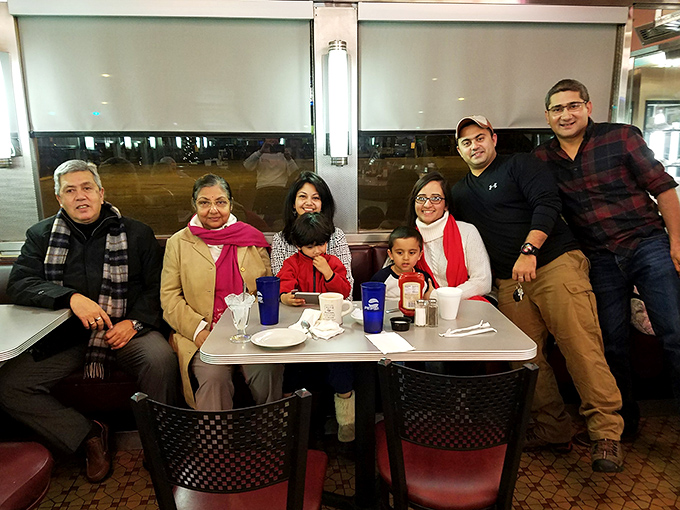 The image shows a group of diners enjoying their meal in one of the comfortable booths that line the restaurant's windows.