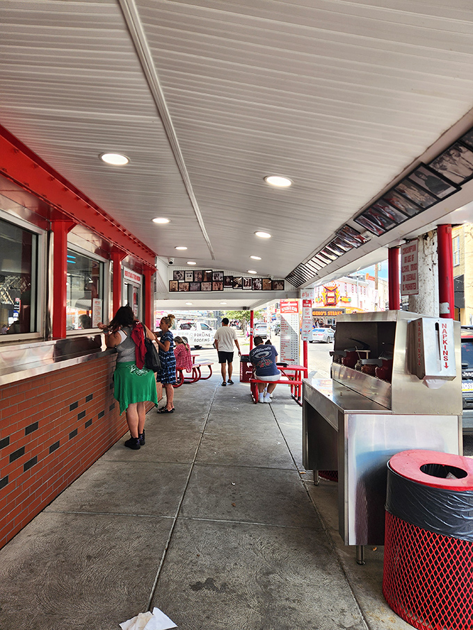 The covered walkway where strangers become friends, united by the universal language of "this sandwich is worth standing for."