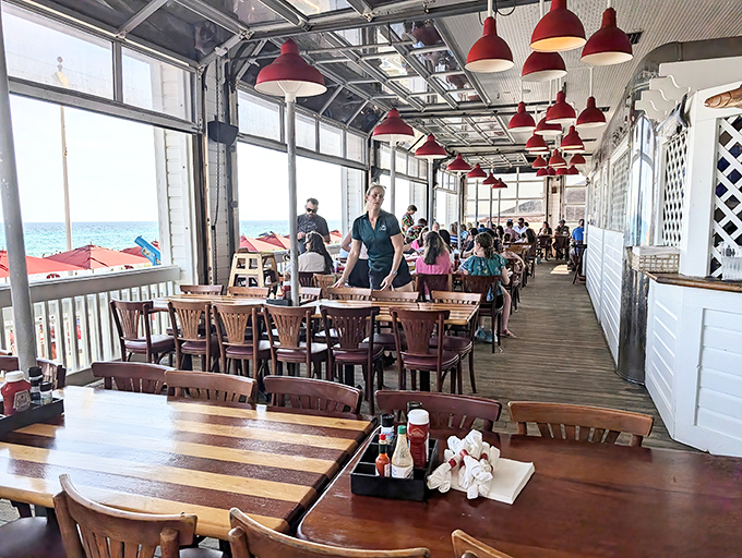 Red pendant lights cast a warm glow over wooden tables where countless vacation memories have been made between bites of fresh seafood.