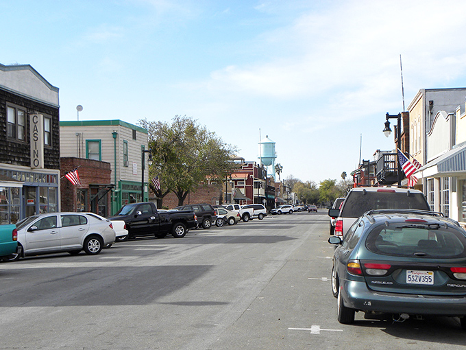 American flags flutter along Isleton's Main Street, where classic cars and historic buildings create a scene that feels delightfully frozen in time.