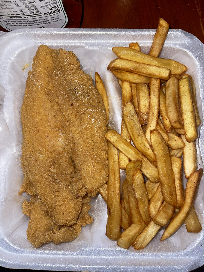 That single catfish fillet commands respect, standing tall beside its french fry army like a cornmeal-crusted general.