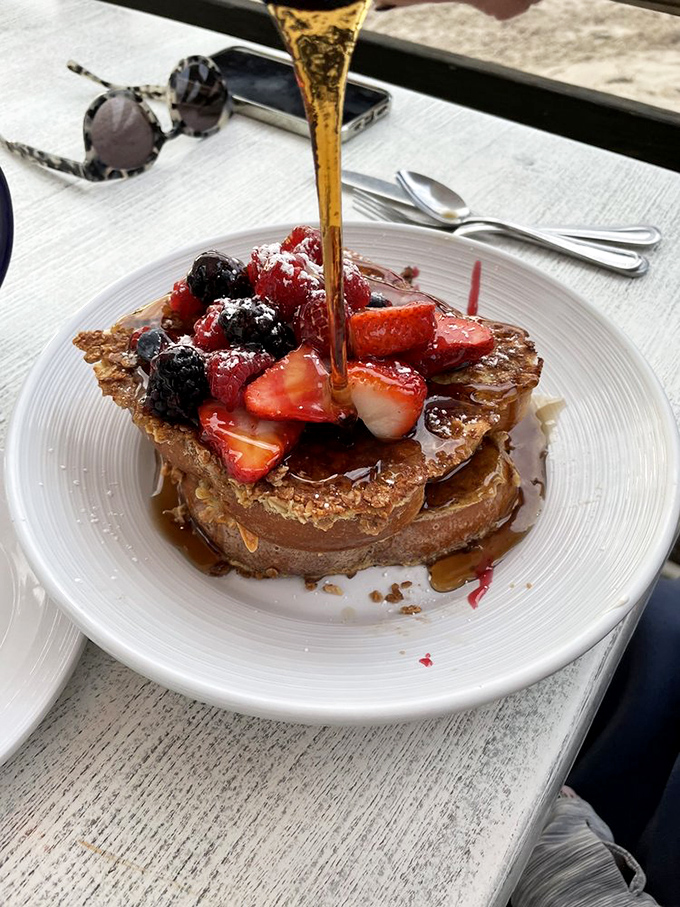 French toast that's having an identity crisis as dessert, complete with berry toppings and a maple syrup waterfall.