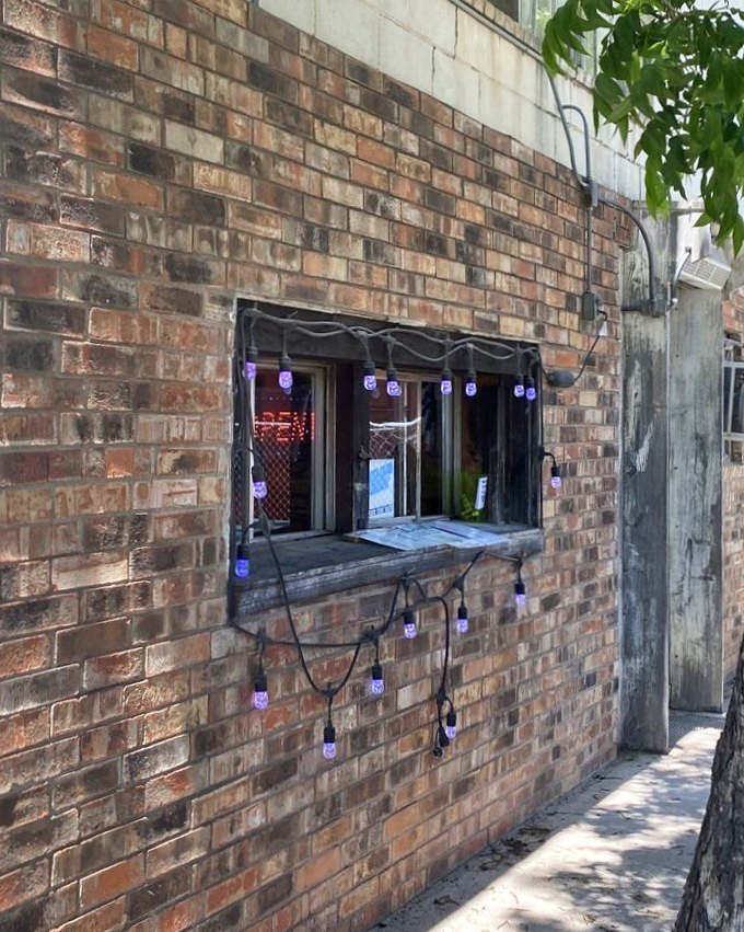 That humble order window, strung with purple lights, might as well be a portal to burger nirvana&mdash;the brick exterior hiding culinary treasures within.