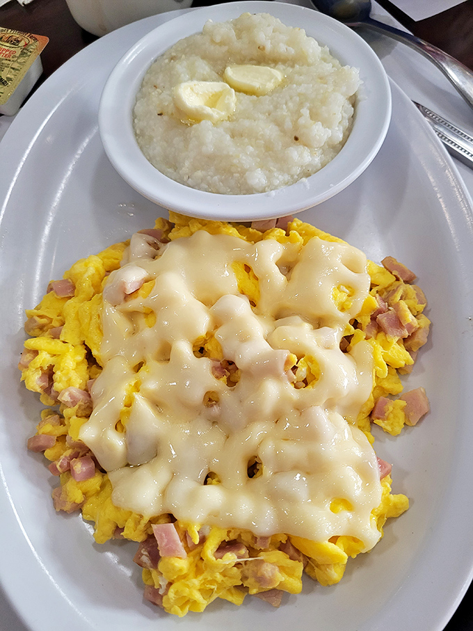 The "Ham Scram" with grits is Southern comfort on a plate. That melted cheese blanket is tucking those eggs in for a flavor nap.