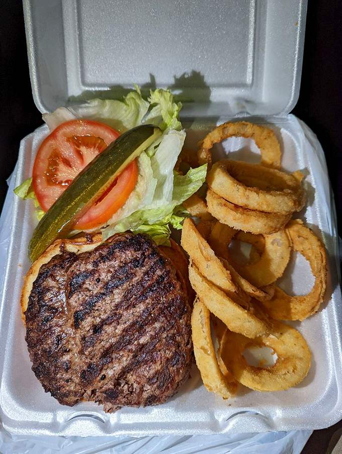 A burger patty with perfect grill marks, nestled beside golden onion rings&mdash;proof that takeout doesn't have to sacrifice quality.