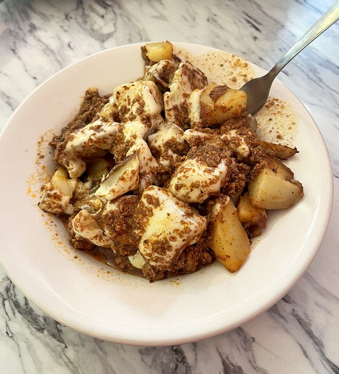 Home fries smothered in what appears to be a savory meat sauce&mdash;potatoes living their best, most indulgent life.