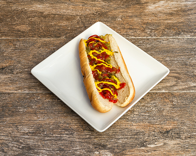 A hot dog that's been elevated beyond ballpark status – dressed with enough toppings to make it worthy of sitting at the BBQ grown-ups table.