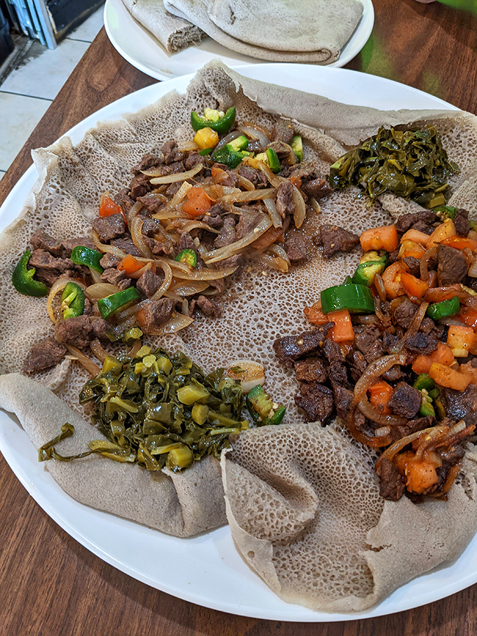A masterclass in communal dining—this injera-lined platter showcases the art of sharing, where every bite tells a different spice-infused story.