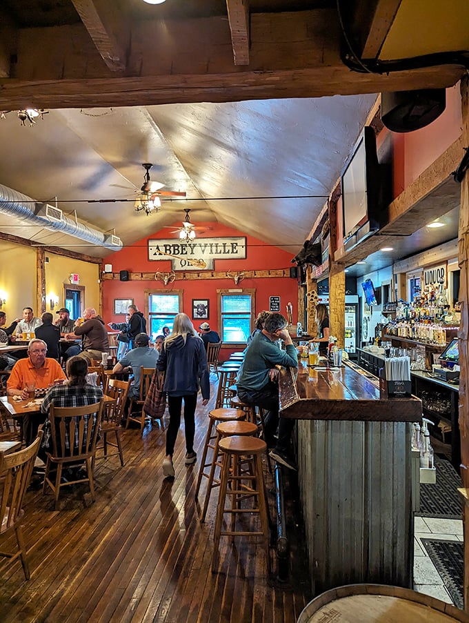 The "Abbeyville" sign watches over happy patrons like a benevolent barbecue deity in this warm, wood-lined gathering space.