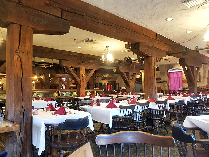 Massive timber beams frame white-clothed tables, creating an atmosphere where rustic charm meets unexpected elegance.