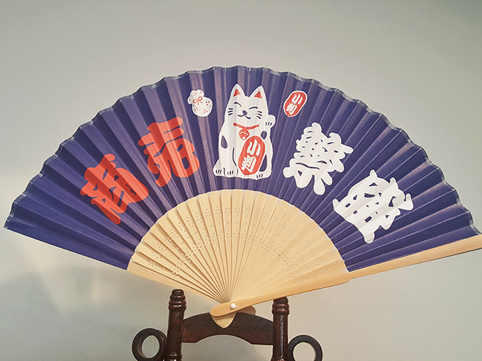 This traditional Japanese folding fan featuring a Maneki-neko (lucky cat) combines art and feline symbolism in one elegant accessory.