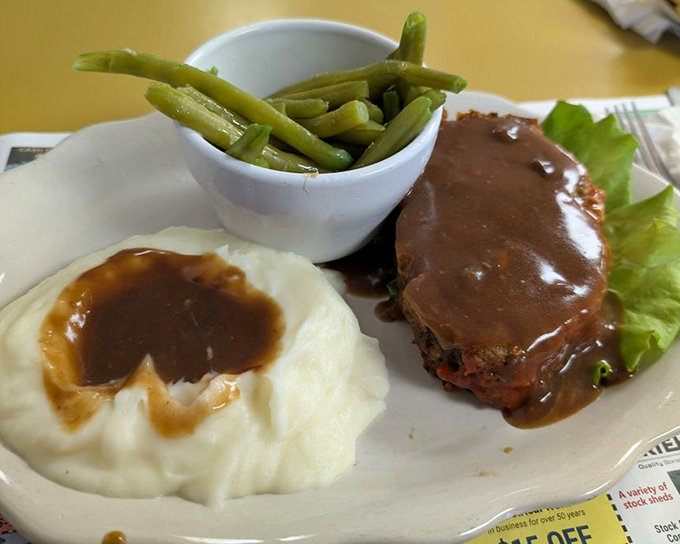 Meatloaf that doesn't apologize for being meatloaf, with gravy pools in mashed potatoes creating the world's most delicious topography.