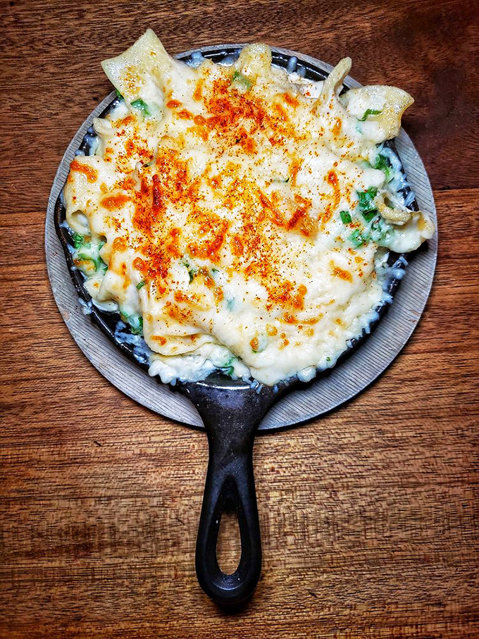 Cast iron comfort food arrives bubbling hot, proving that some dishes are worth sharing with newfound friends.