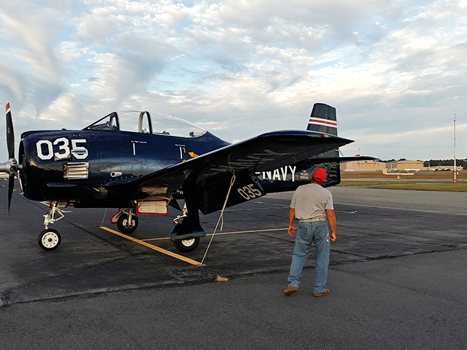 A classic Navy trainer awaits its next mission while a visitor contemplates the courage it took to fly these machines in combat conditions.