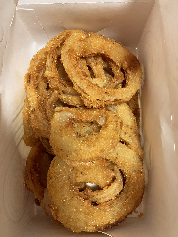 Onion rings so perfectly stacked they could teach geometry. The hand-breading process isn't just cooking—it's architecture for your appetite.