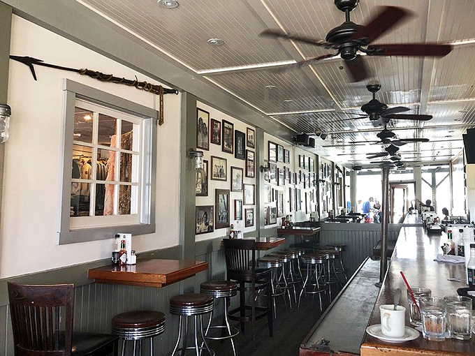 Nautical nostalgia meets culinary comfort. The black and white photos tell stories of the sea while ceiling fans keep the ocean breeze company.