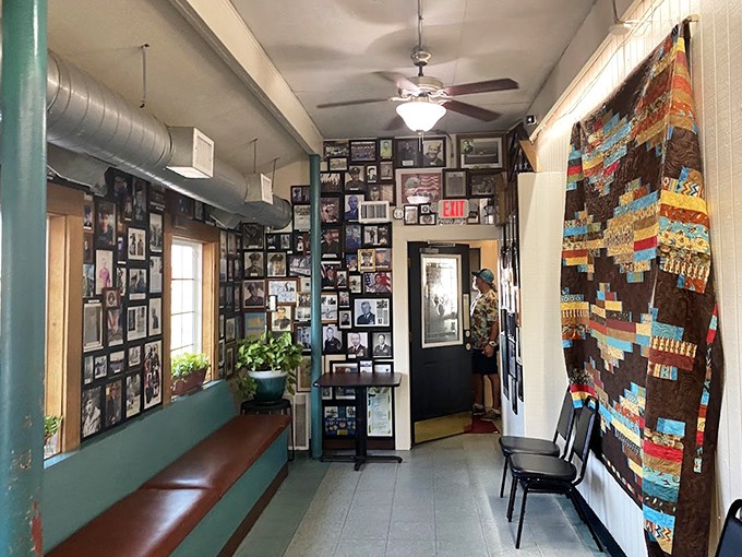 A hallway lined with community photos and a handmade quilt—this isn't decoration, it's the visual story of West Side Cafe's place in Fort Worth.