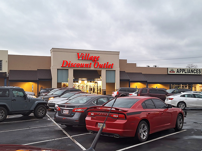 Even at dusk, the Village Discount Outlet's glow attracts a steady stream of cars, like moths to a flame-colored discount sign.