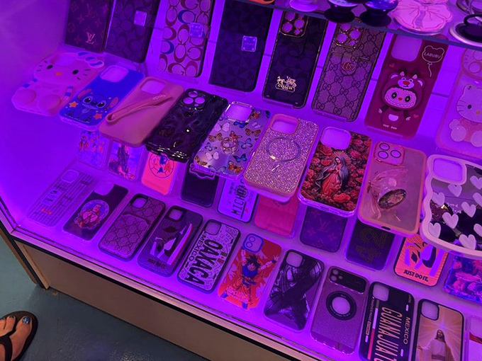 Phone case paradise illuminated by purple light, where your mobile can dress more expressively than most people at the grocery store.