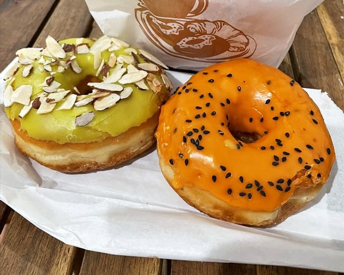 Two donuts that prove variety is the spice of life. The pistachio with its nutty crown sits proudly next to its Thai Tea companion.