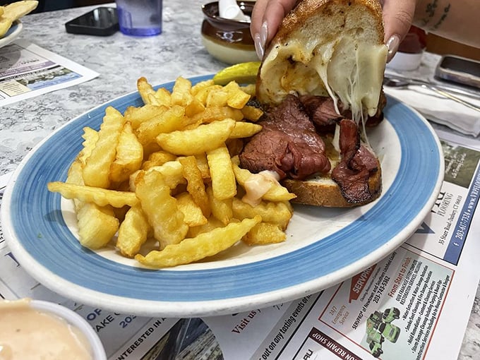 This isn't just a sandwich&mdash;it's a Reuben masterpiece with melted cheese cascading over tender meat, demanding to be photographed before it's devoured.