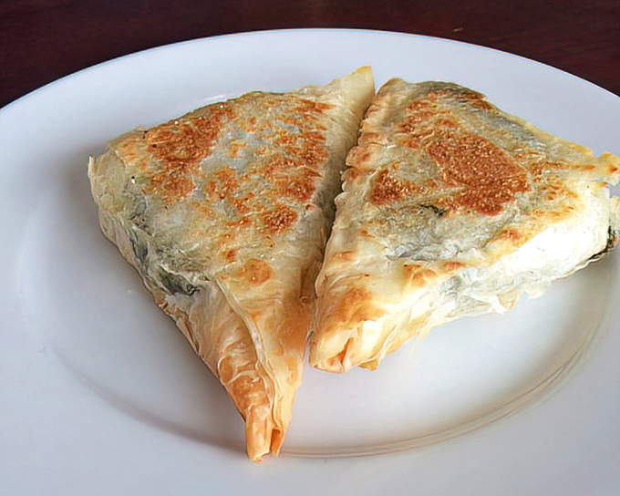 Spanakopita that achieves the impossible: phyllo dough so flaky it creates its own weather system, cradling spinach and feta in perfect harmony.