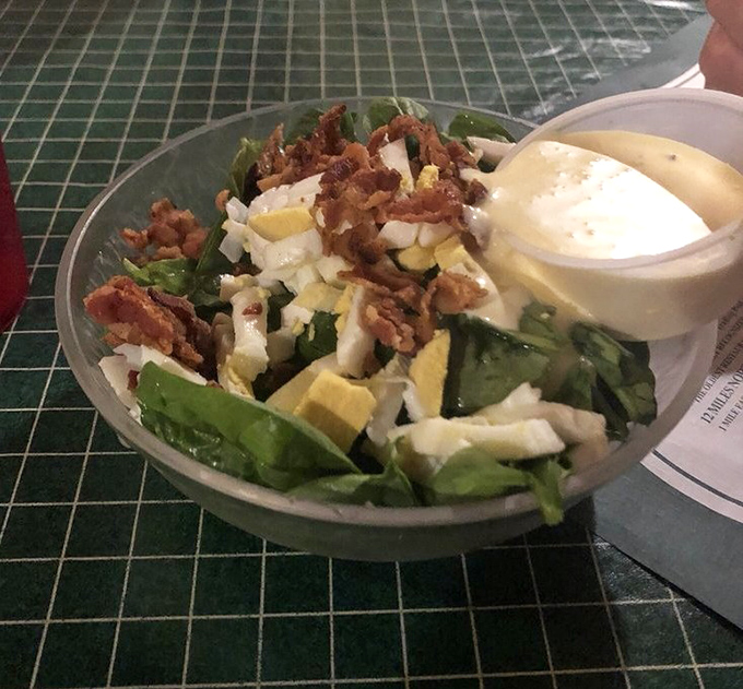 A fresh spinach salad offers a token nod to nutrition, though the bacon and egg suggest it's not trying too hard to be virtuous.