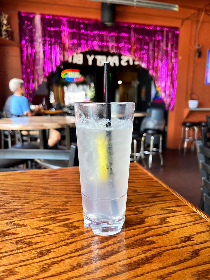 A tall glass of refreshment sits before vibrant d&eacute;cor. Sometimes the simplest drinks are the perfect palette cleansers between pizza slices.