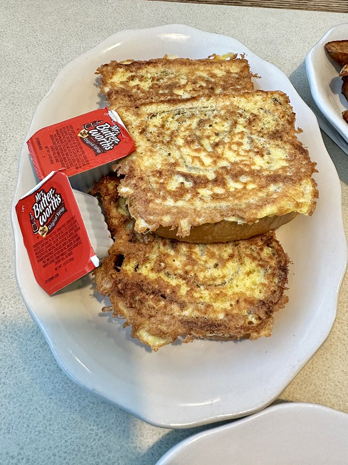 Golden-brown French toast that's achieved that mythical balance &ndash; crispy exterior giving way to custardy insides, with butter packets standing by for duty.