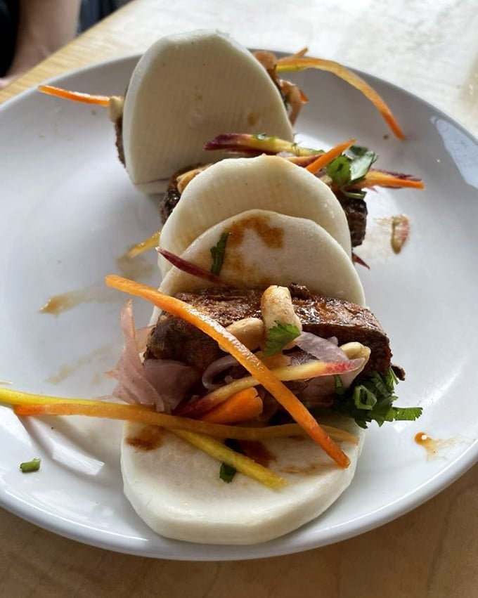 These bao buns cradle their fillings like precious cargo, topped with vibrant veggies that add both crunch and color to every perfect bite.