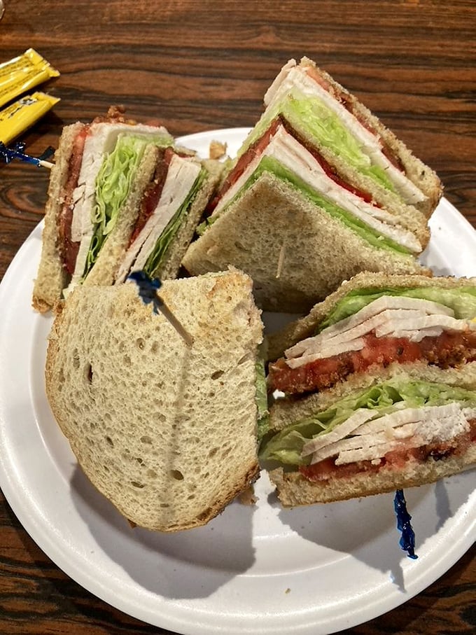 A club sandwich built like architectural brilliance&mdash;layers of fresh ingredients stacked with engineering precision. The toothpicks are structural support for this masterpiece.