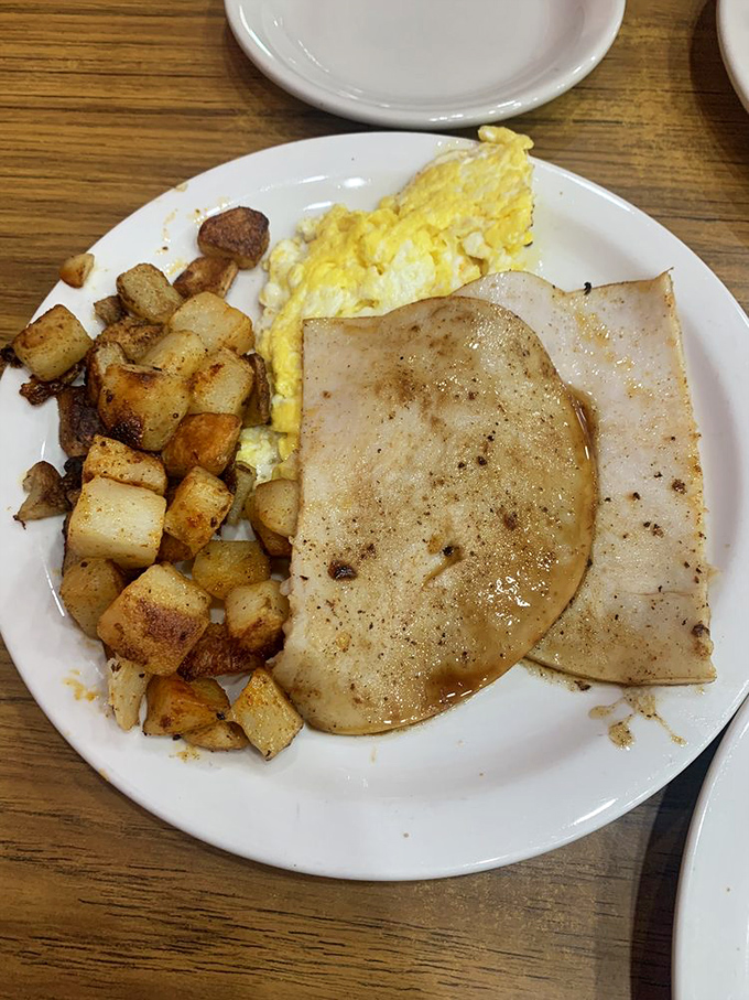 Breakfast perfection: golden eggs with yolks ready to burst, seasoned potatoes, and sausage patties that didn't come from any freezer section.