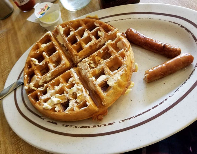 Golden waffle perfection with sausage links standing at attention&mdash;a breakfast plate that says "Good morning" with more enthusiasm than you can muster before coffee.