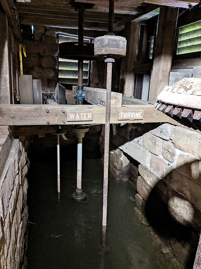 The mill's water turbine system stands frozen in time, a mechanical marvel that once harnessed the creek's power to transform wheat into the staff of life.