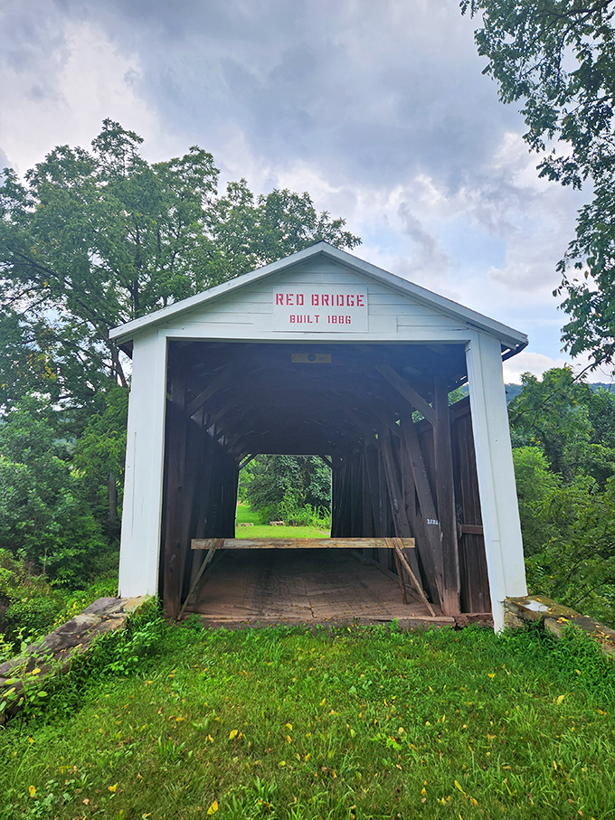 Storm clouds gather dramatically above, creating a moody backdrop that highlights the bridge's brilliant white portals and weathered planking.