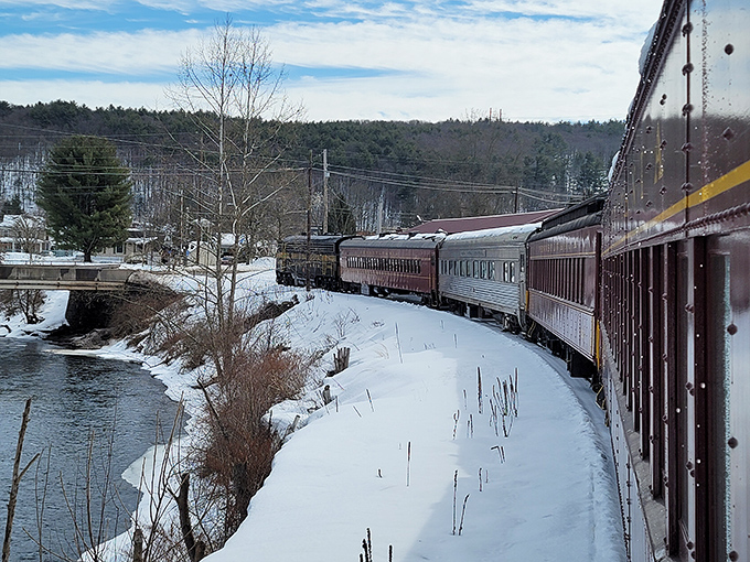 Winter transforms the journey into a Currier and Ives print come to life, with snow-dusted banks and ice-fringed waters creating a seasonal masterpiece outside every window.