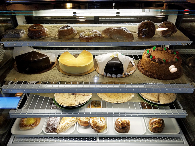 The dessert case – where willpower goes to surrender unconditionally. Each shelf offers a different path to sweet satisfaction and zero regrets.