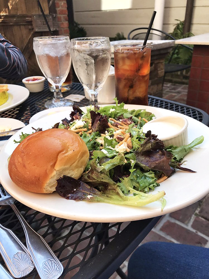 Outdoor dining with mixed greens, fresh rolls, and cold drinks&mdash;proof that salad can be the main character when the setting is this charming.