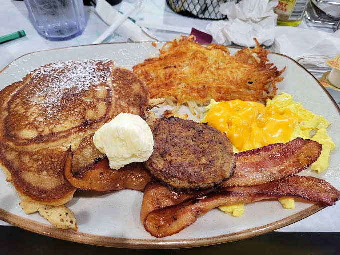 Breakfast of champions: golden pancakes, crispy bacon, savory sausage, and eggs that would make a rooster proud. Morning glory on a plate.
