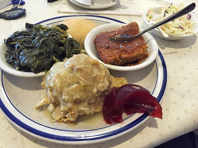 Southern comfort on a plate: collard greens, mashed potatoes with gravy, and what appears to be meatloaf - a hug in food form.