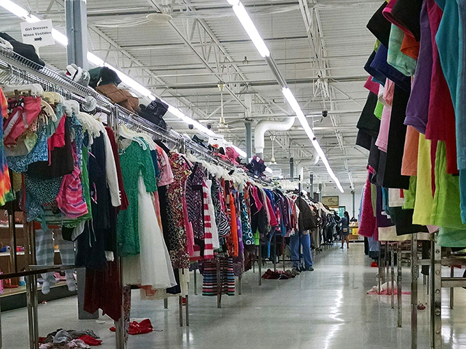 A rainbow of possibilities stretches down the clothing aisle, each hanger holding a garment with its own story and potential future.
