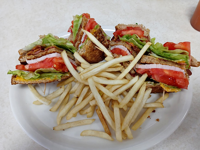 A club sandwich that stands tall and proud, with layers of goodness between toasted bread. The fries standing at attention know they're in good company.