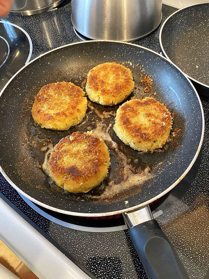 Golden crab cakes sizzling in the pan, ready to fulfill their destiny as the highlight of someone's very lucky day.